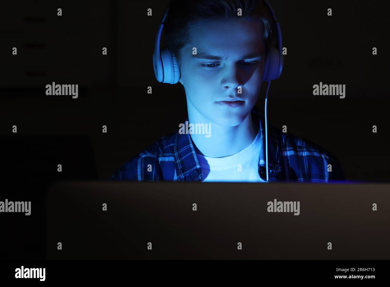 Teenage boy in headphones using computer at night. Internet addiction ...