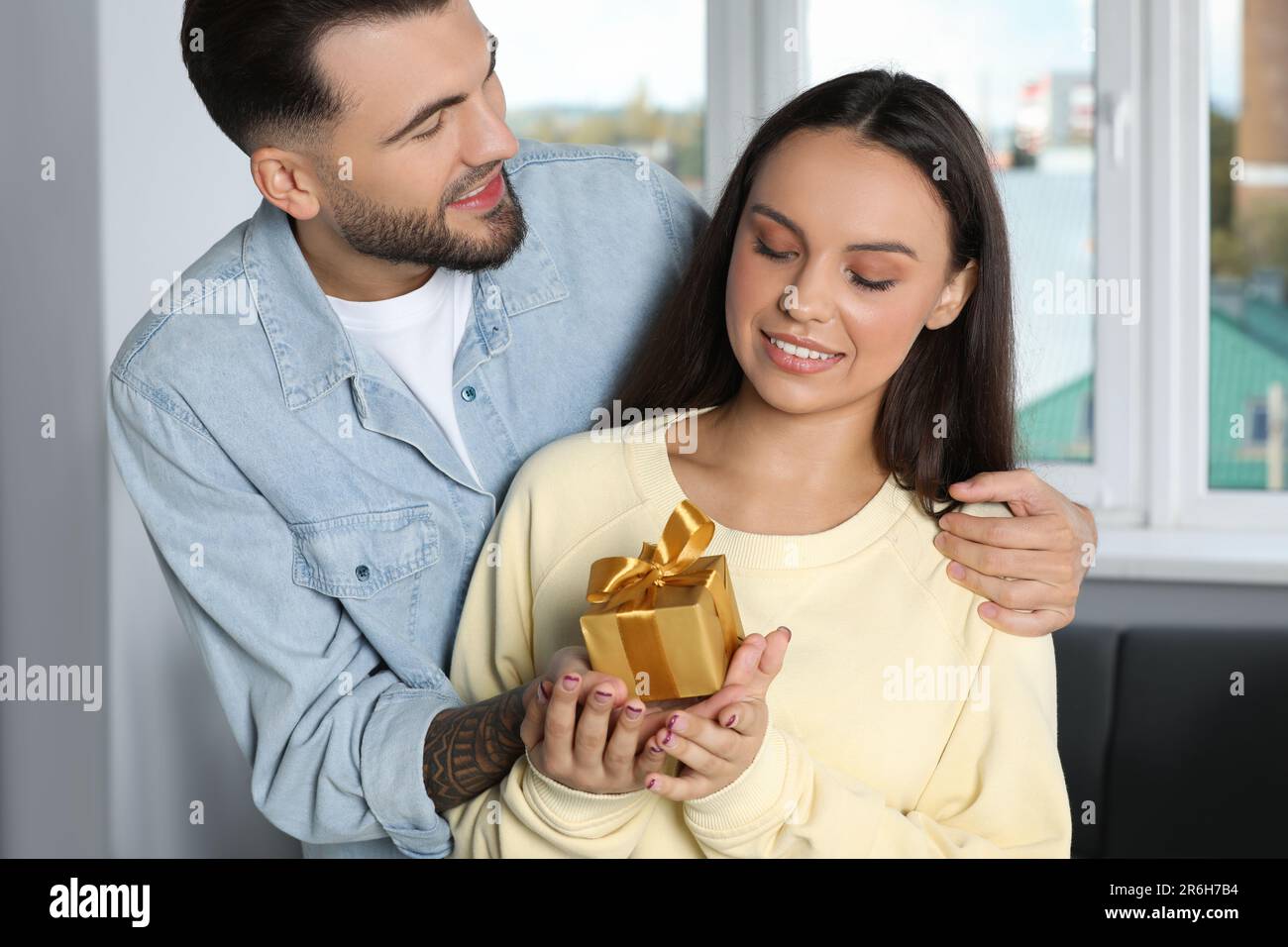 Man presenting gift to his girlfriend at home Stock Photo - Alamy