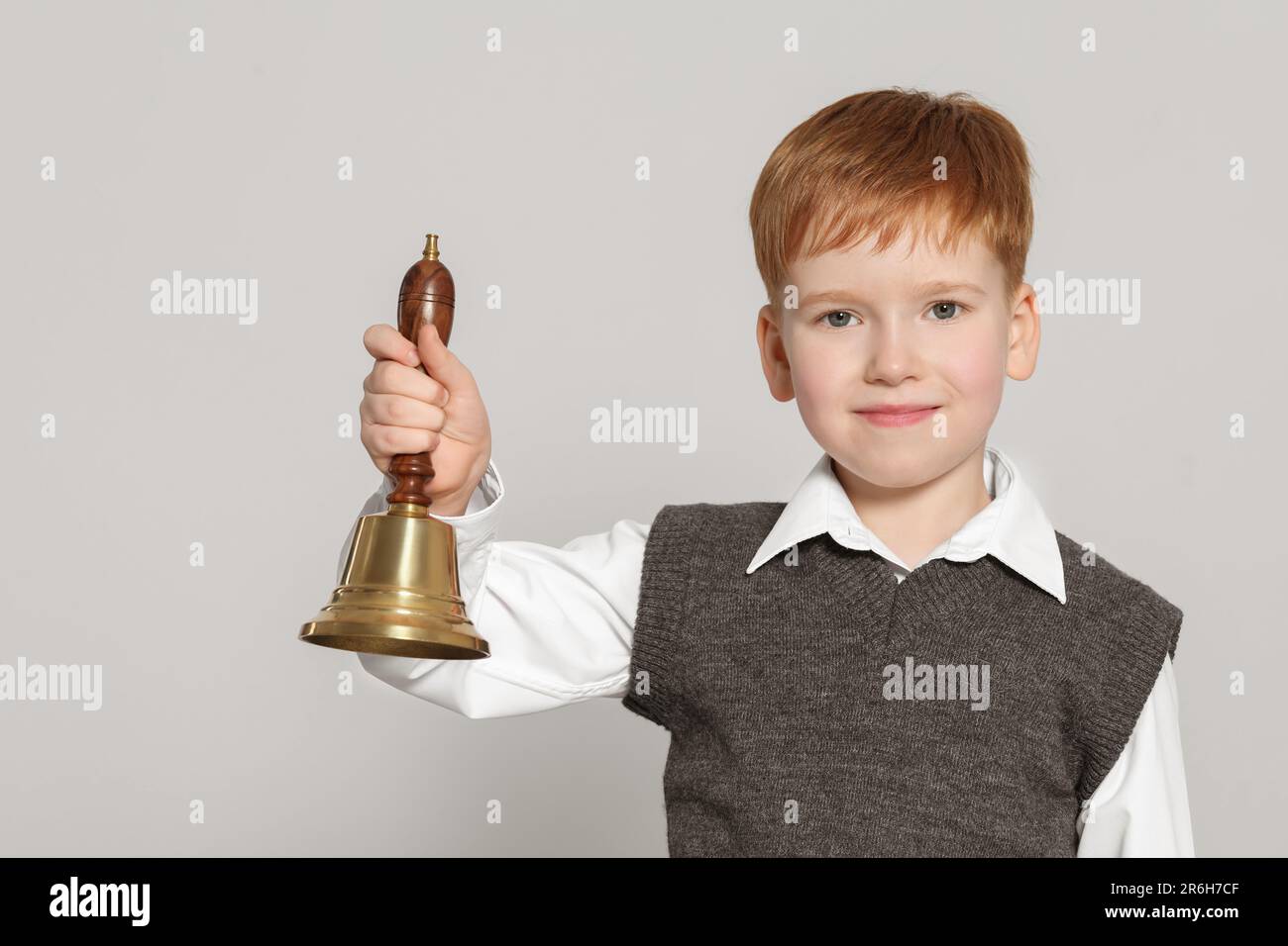 Pupil with school bell on light grey background Stock Photo - Alamy