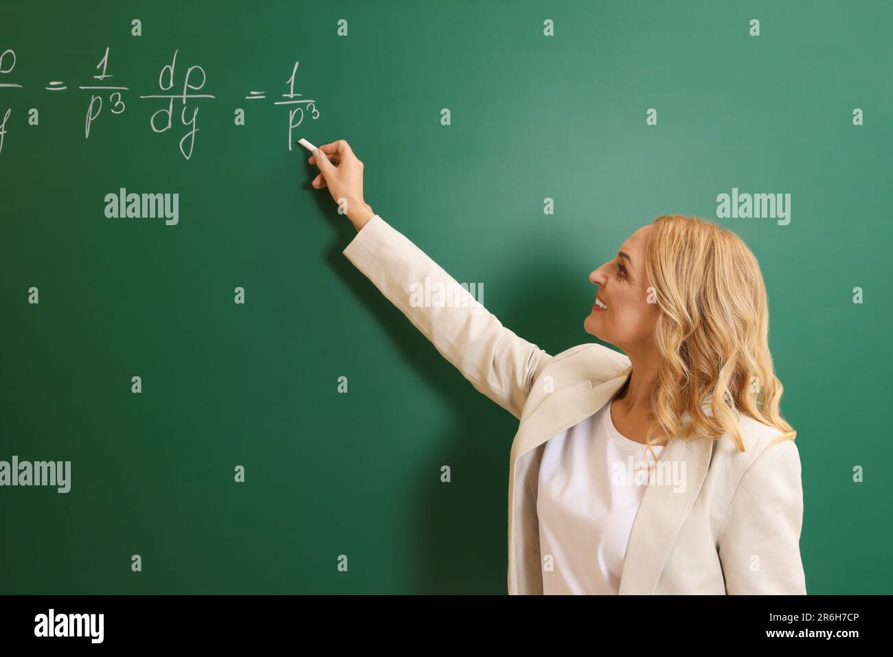 Professor writing down math equation on green board Stock Photo - Alamy