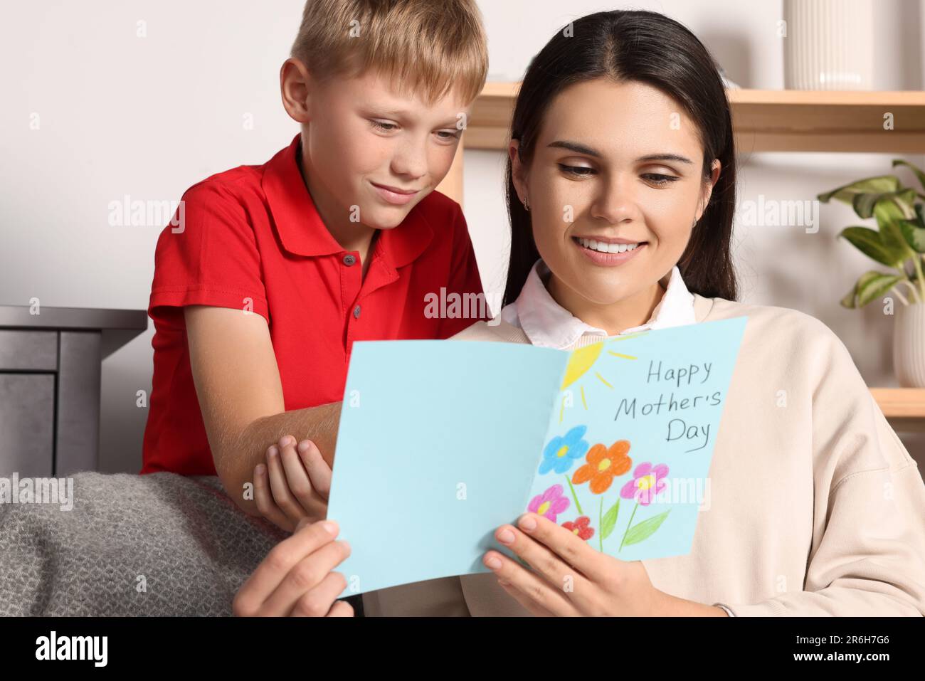 Happy woman receiving greeting card from her son at home Stock Photo ...