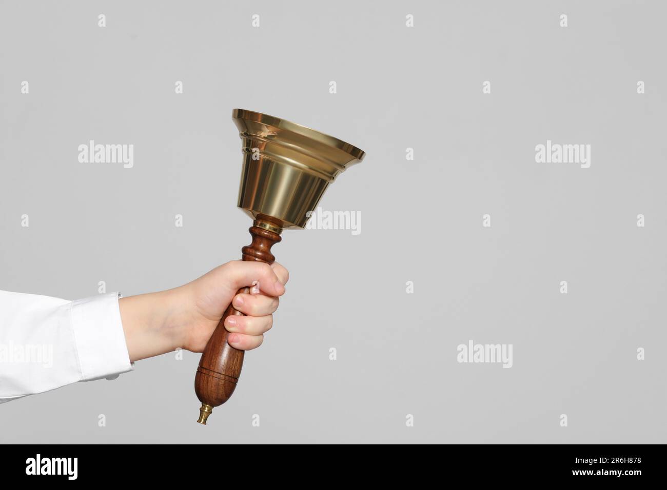 Pupil with school bell on light grey background, closeup. Space for ...