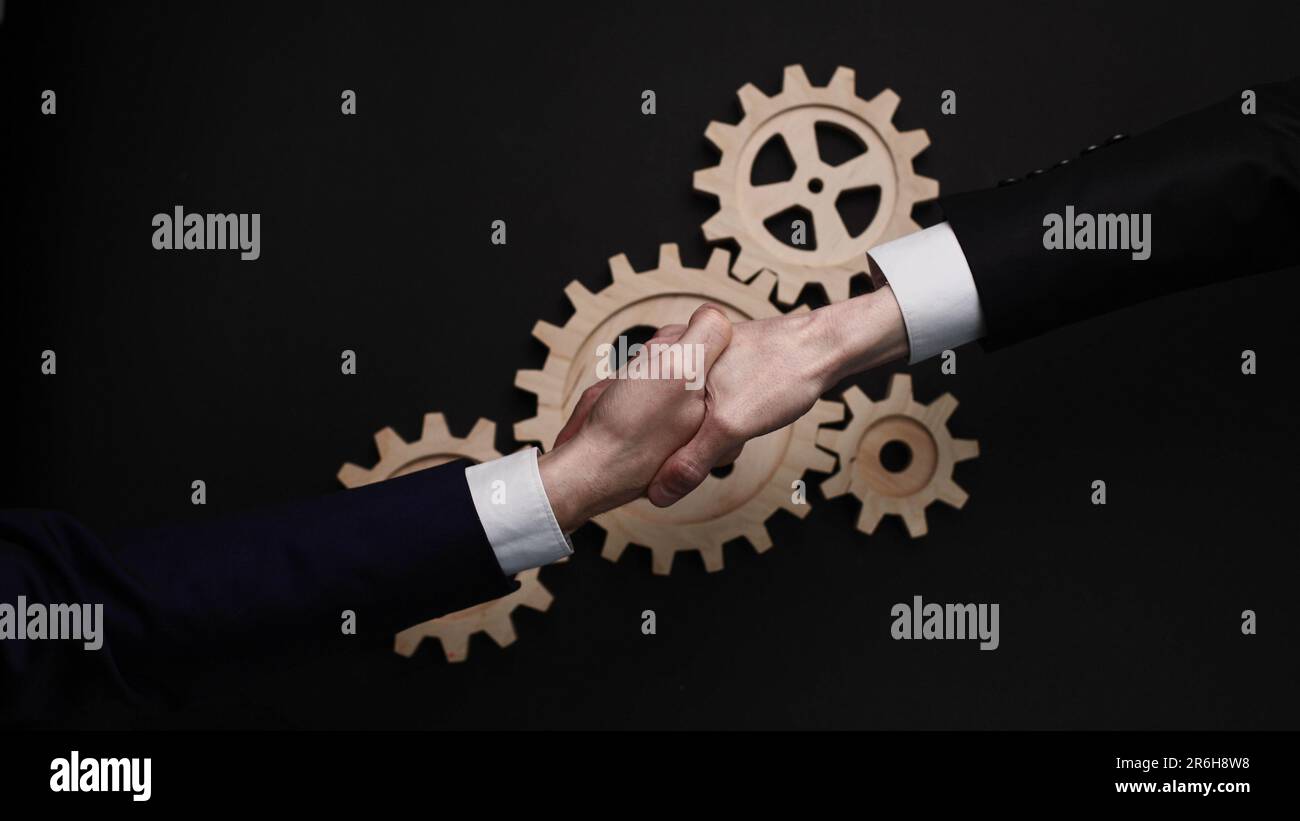 Two businessmen shaking hands on a black background. The concept of a ...