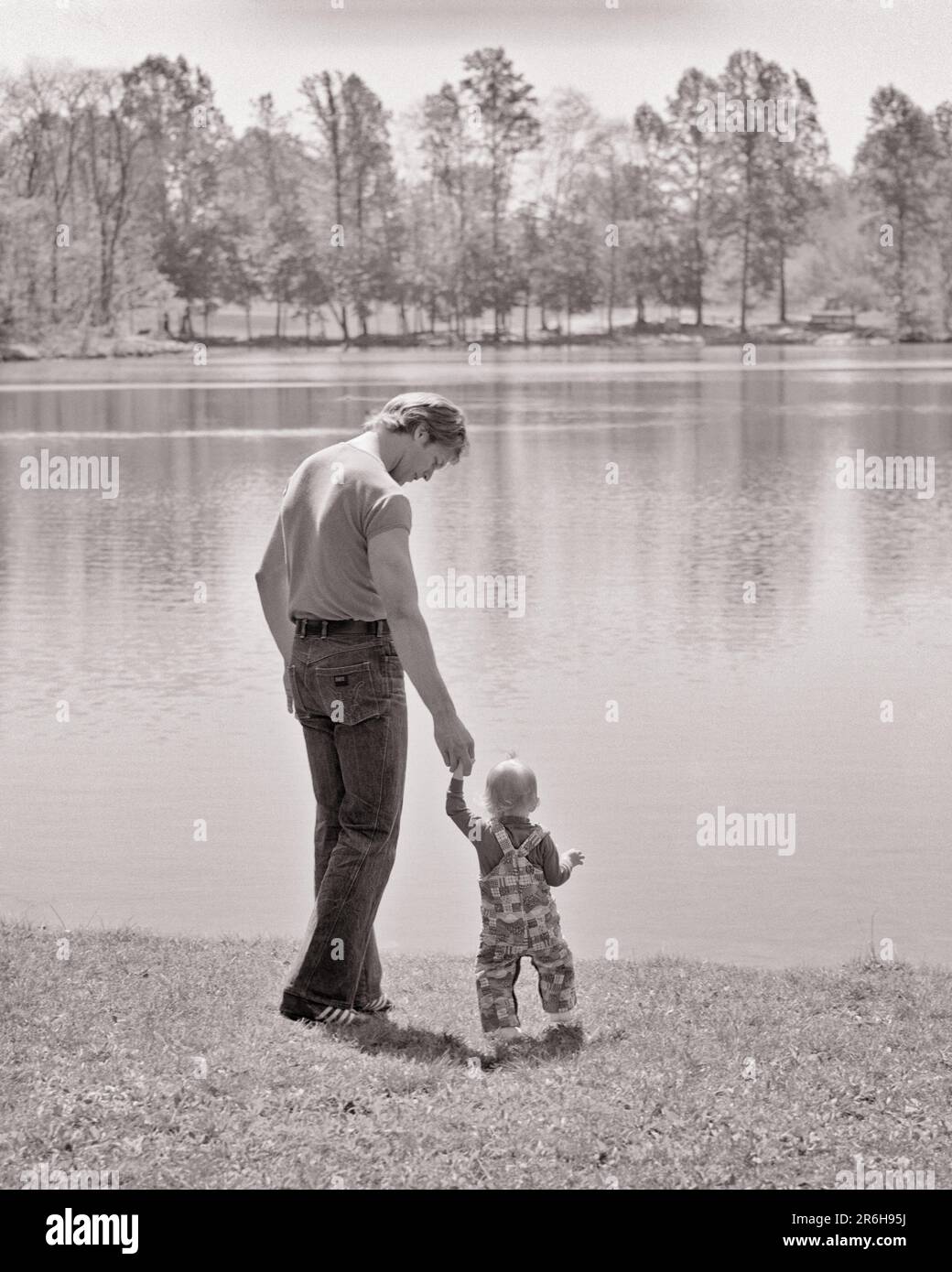 1970s FATHER WALKING HOLDING HANDS WITH TODDLER SON NEAR LAKE - b25773 ...
