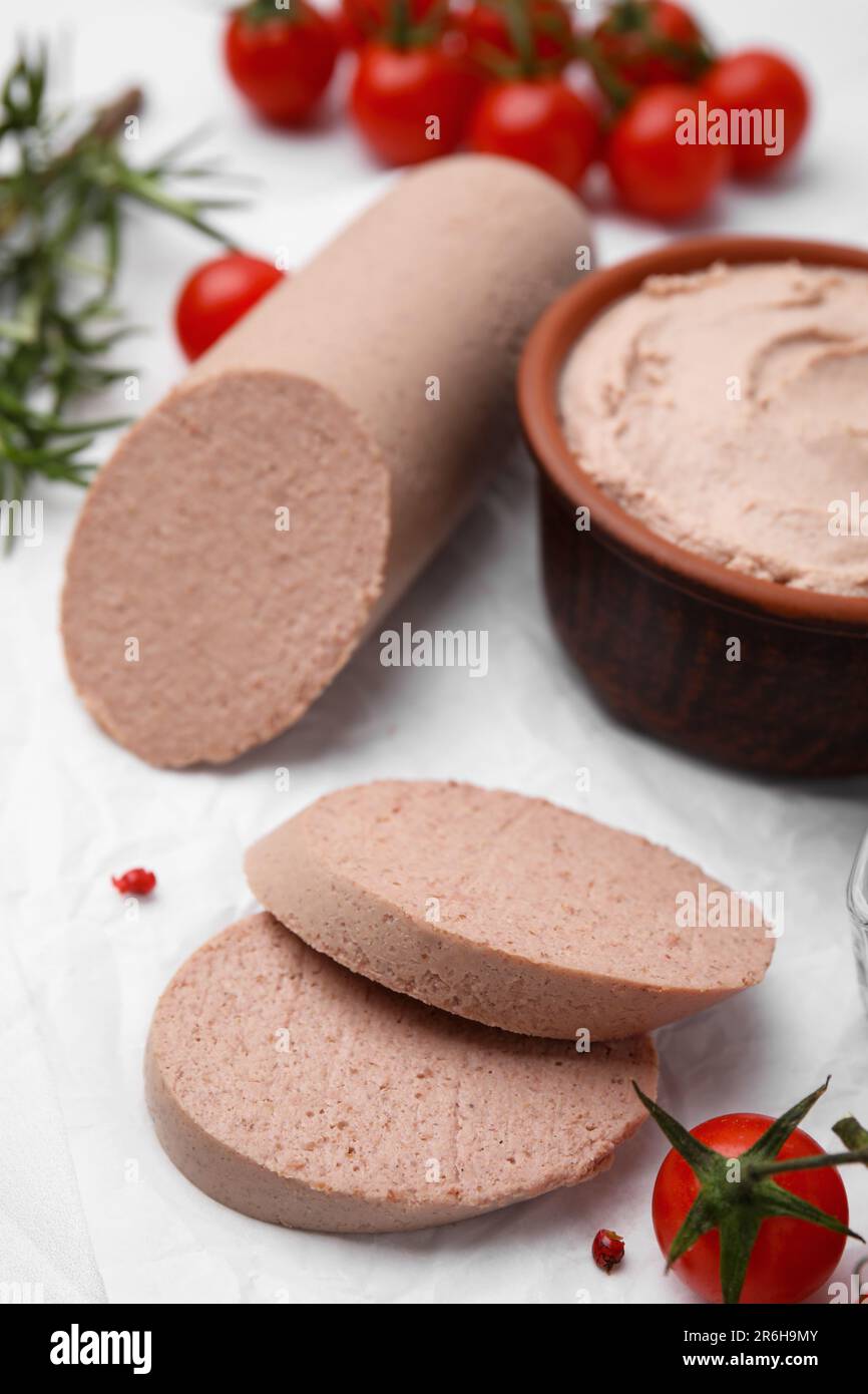 Delicious liver sausage, paste and other products on white tiled table ...