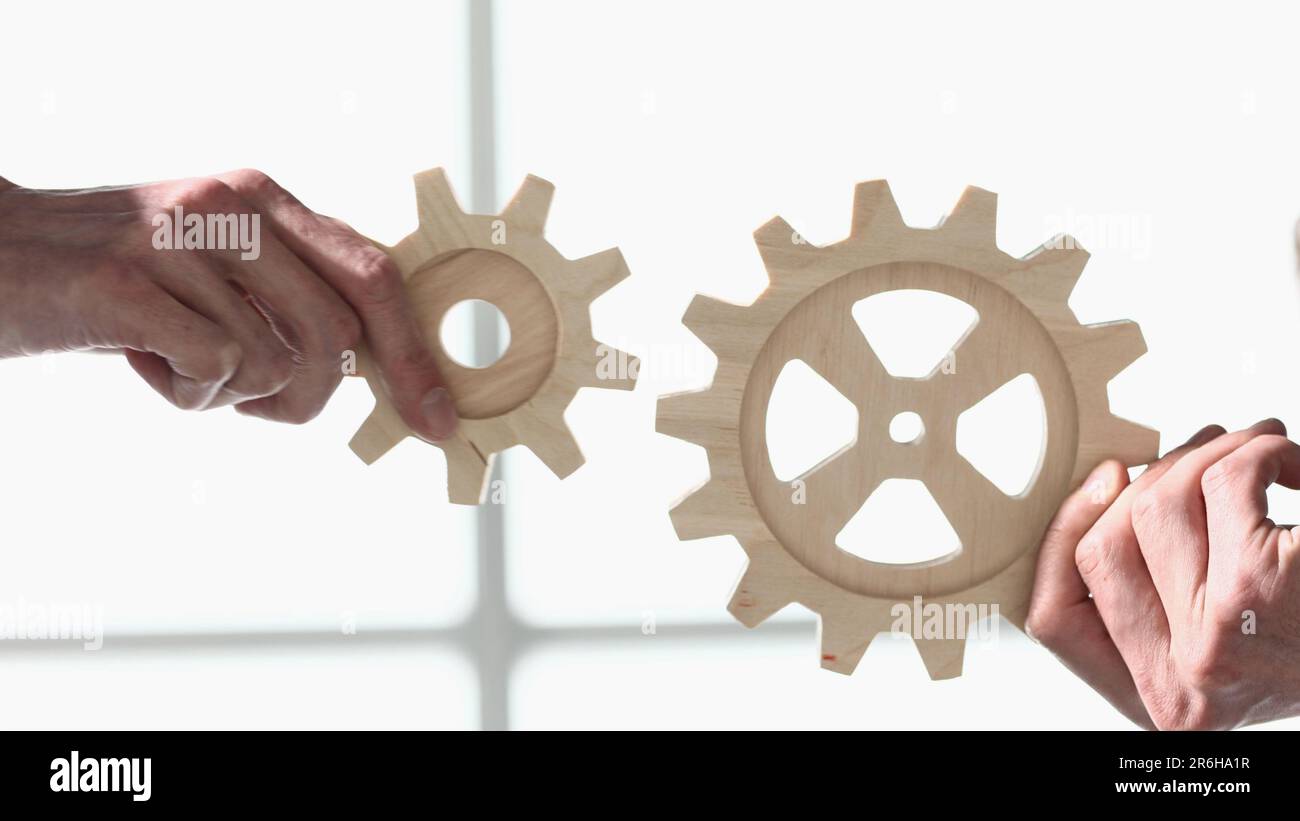 Businessmen in suits connect gears as a symbol of business processes in ...