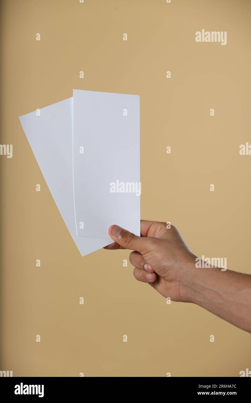 Man holding flyers on beige background, closeup. Mockup for design ...