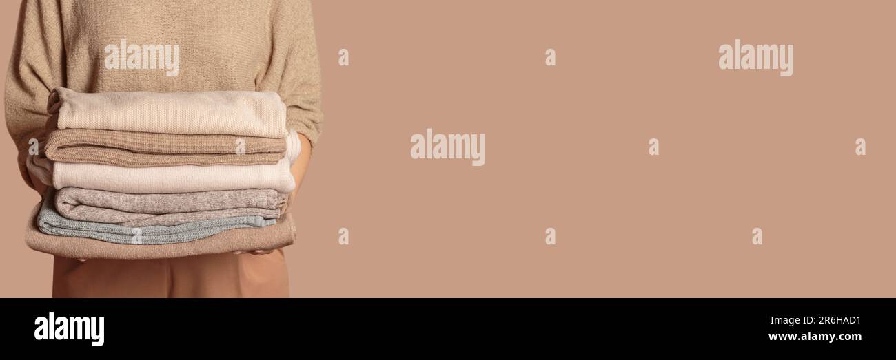 Woman holding stack of clothes with used wardrobe, ready to give away ...