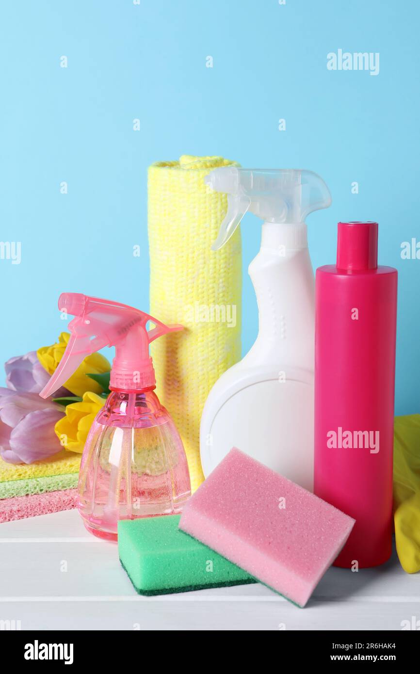 Spring cleaning. Detergents, flowers and sponges on white wooden table ...