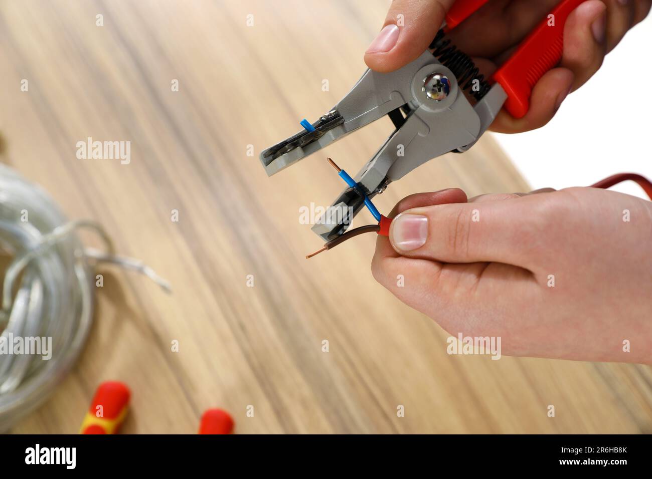 Professional electrician stripping wiring at wooden table, top view ...