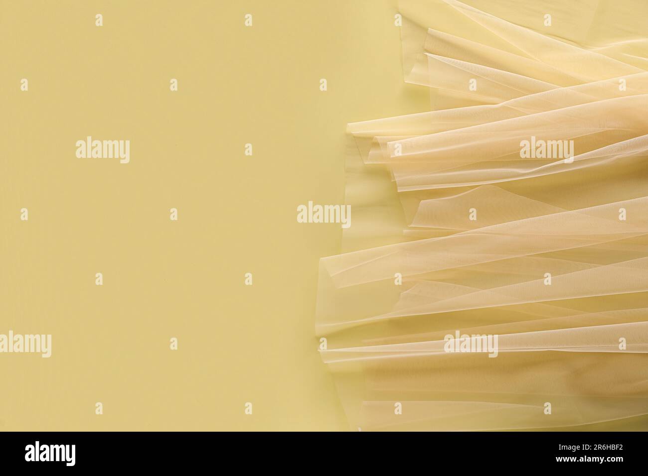 Beautiful tulle fabric on yellow background, top view. Space for text ...