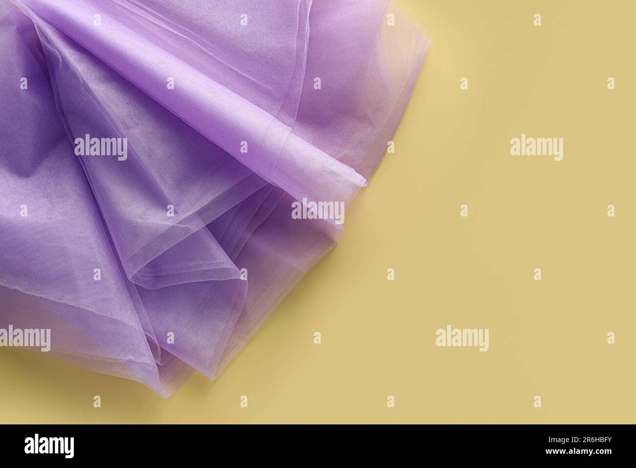 Beautiful tulle fabric on yellow background, top view. Space for text ...