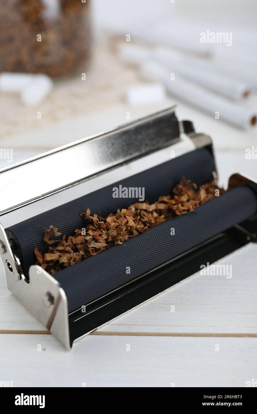 Roller with tobacco on white wooden table, closeup. Making hand rolled ...