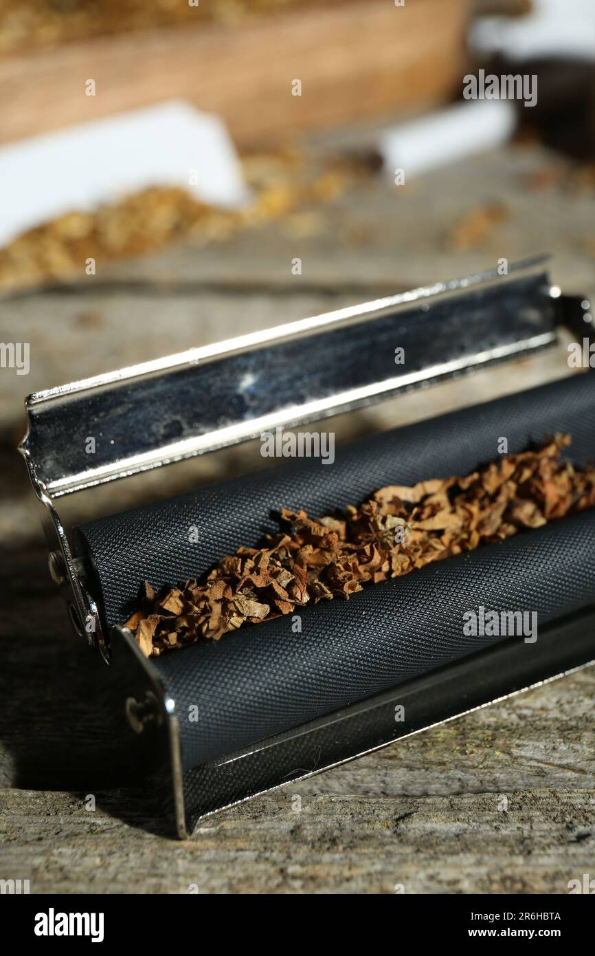 Roller with tobacco on old wooden table, closeup. Making hand rolled ...