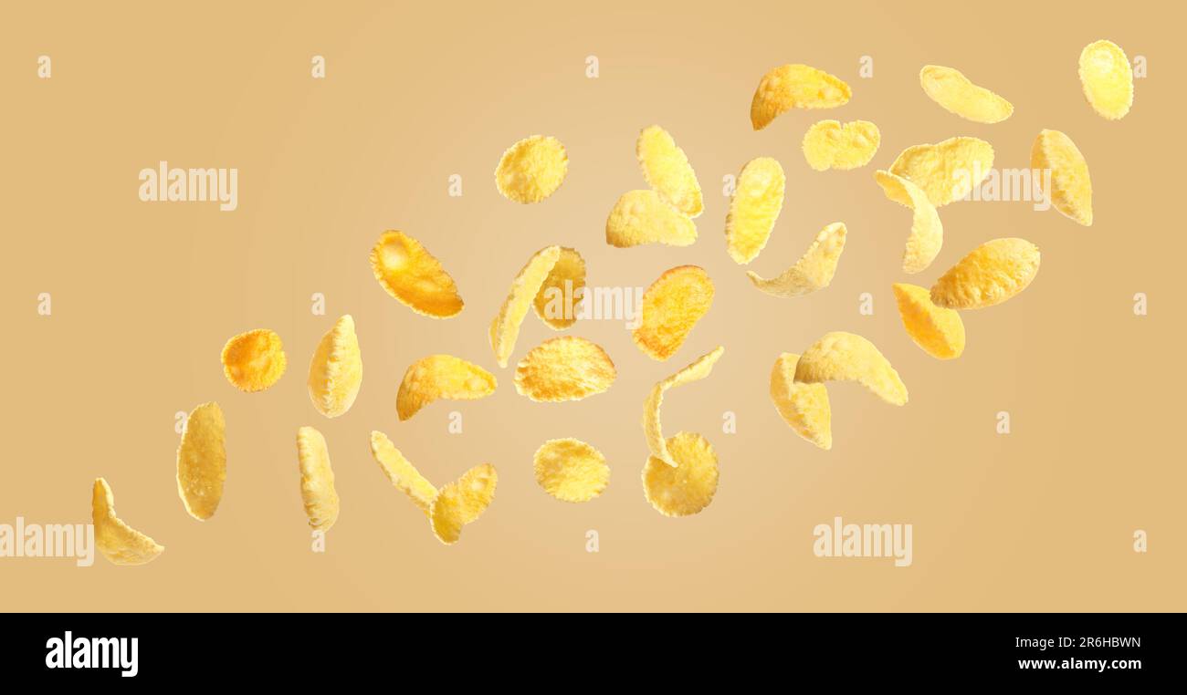 Many tasty corn flakes flying on pale orange background Stock Photo - Alamy