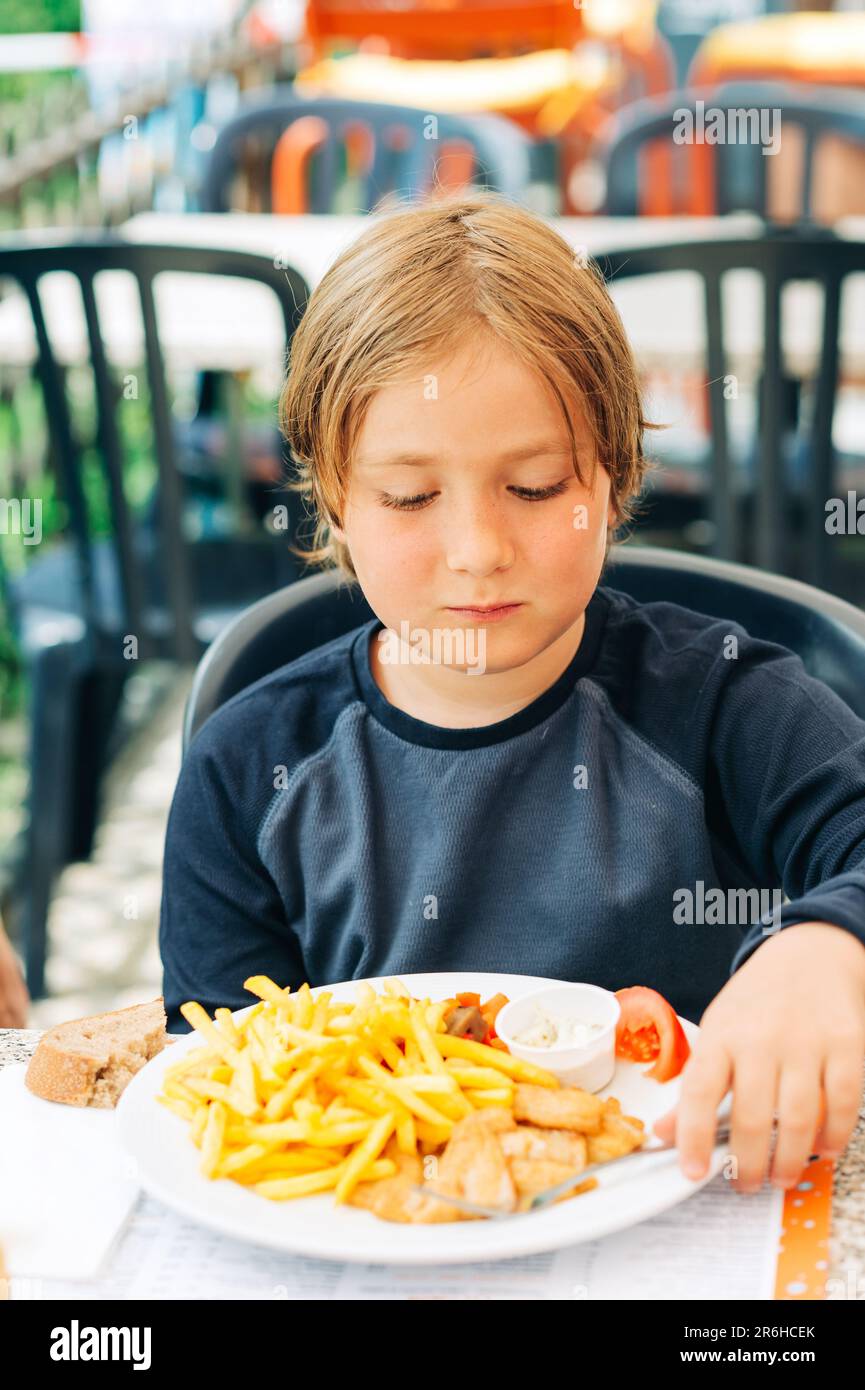 Child eating french fries and chicken nuggets in outdoor restaurant ...