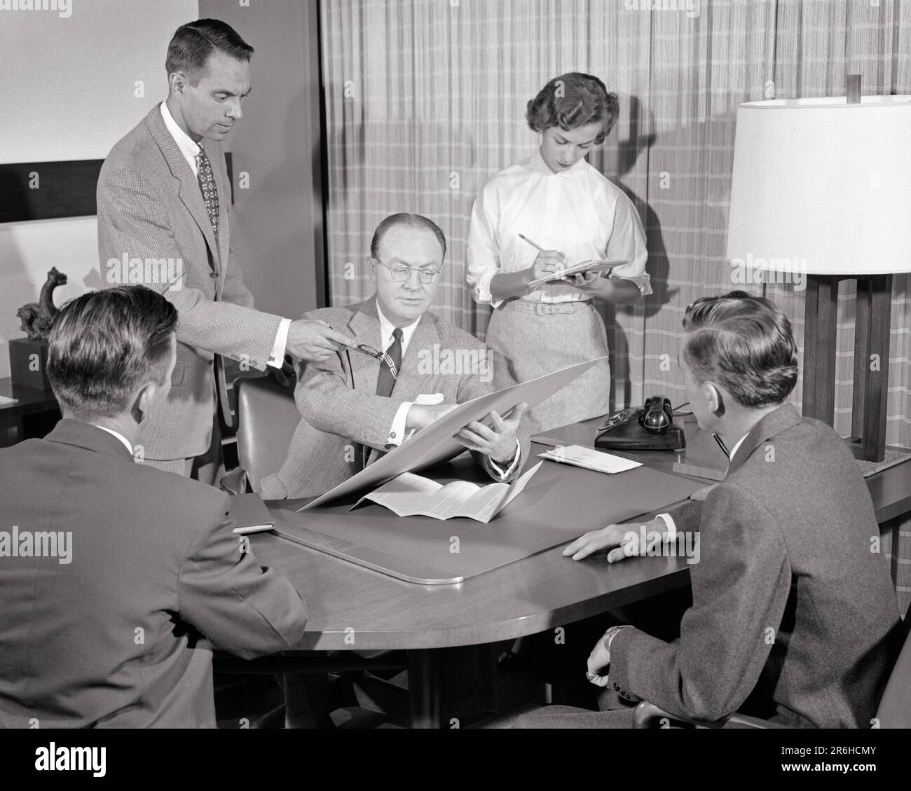 1950s FOUR MEN EXECUTIVES IN OFFICE REVIEWING AND DISCUSSING A BUSINESS ...