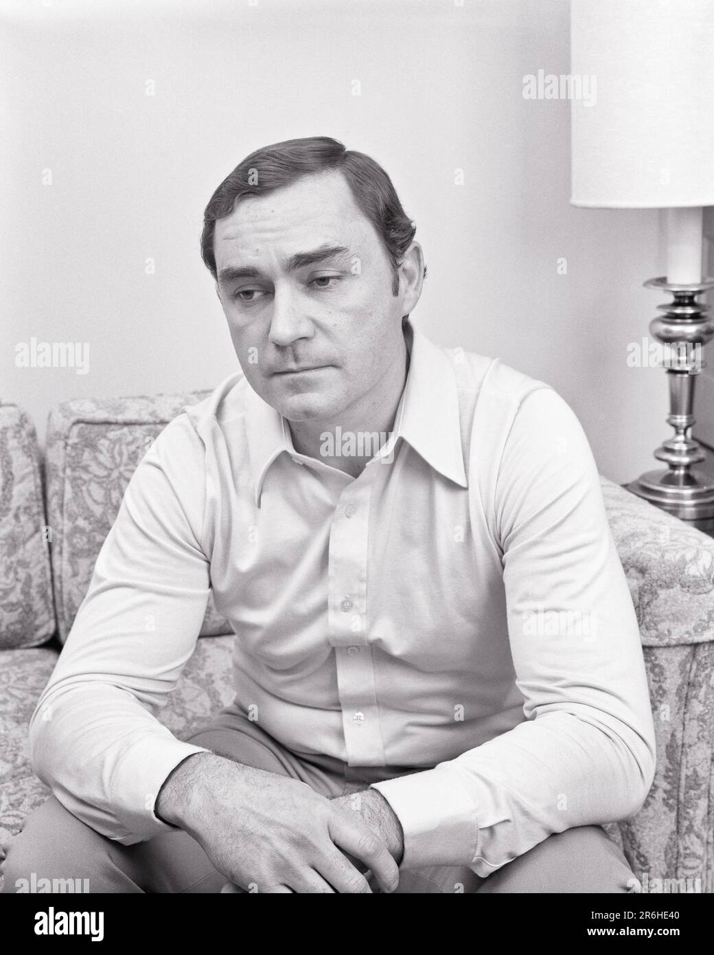 1970s BRUNETTE MAN SITTING ON LIVING ROOM COUCH LOOKING DOWN WITH SAD ...