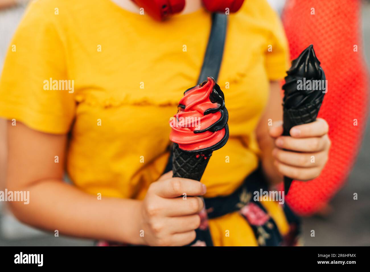 Young teen girl holding red and black ice cream, street food festival ...