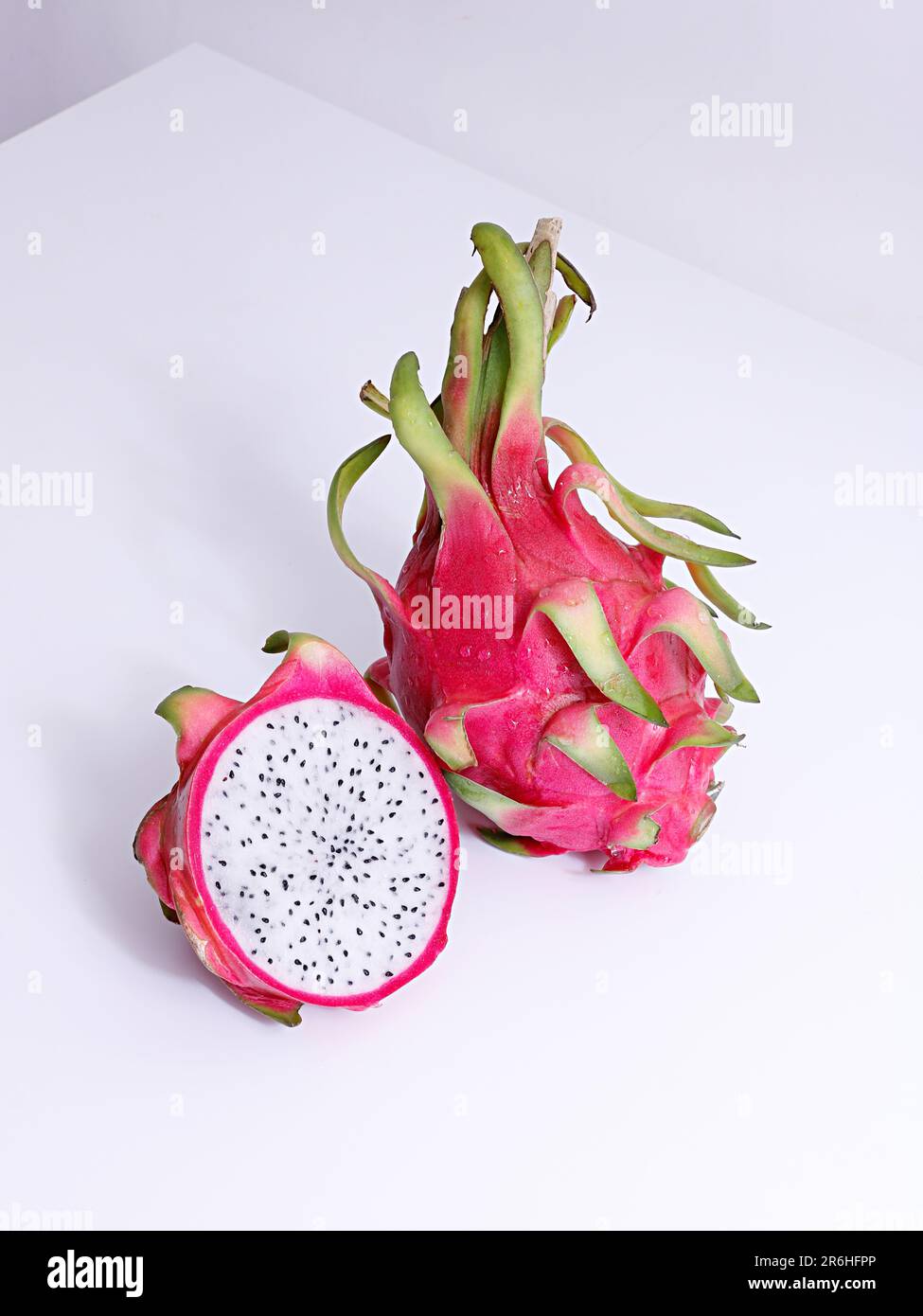 A close-up of a cut dragon fruit, showing the vibrant pink and green ...