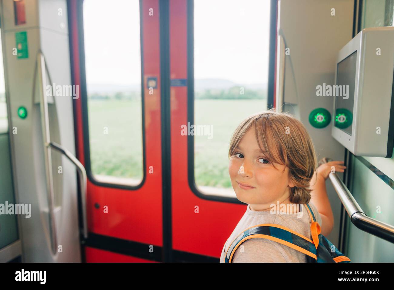 Little boy travel by train, standing next to exit, waiting for the stop ...