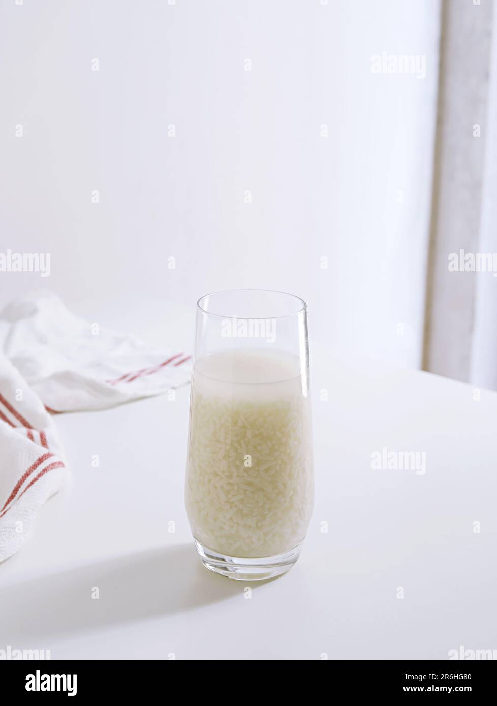 A crystal clear glass filled to the brim with white rice submerged in ...