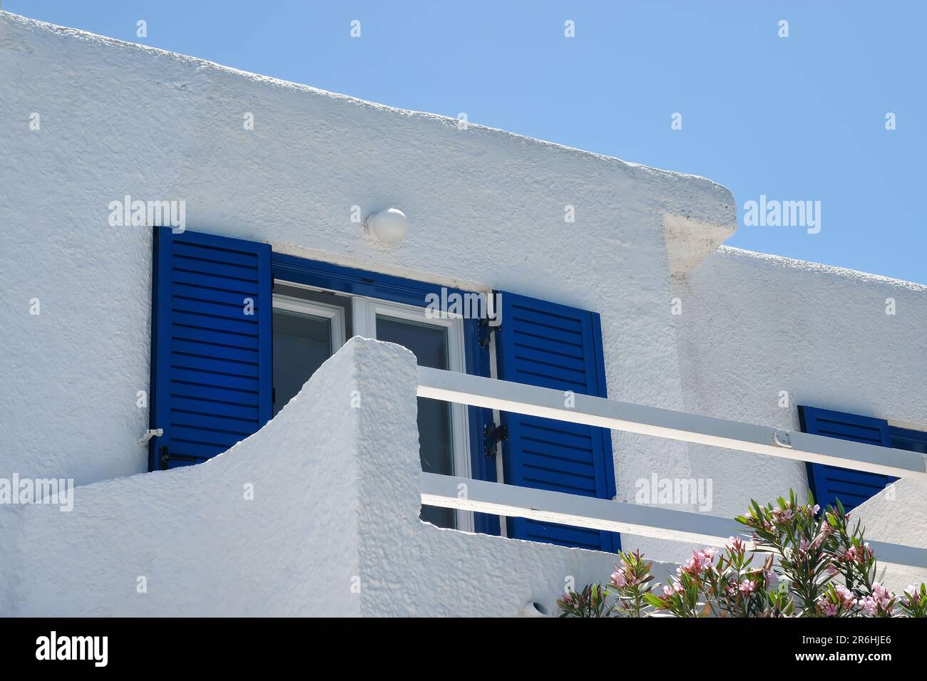 A white washed house with blue window shutters and a balcony in Ios ...