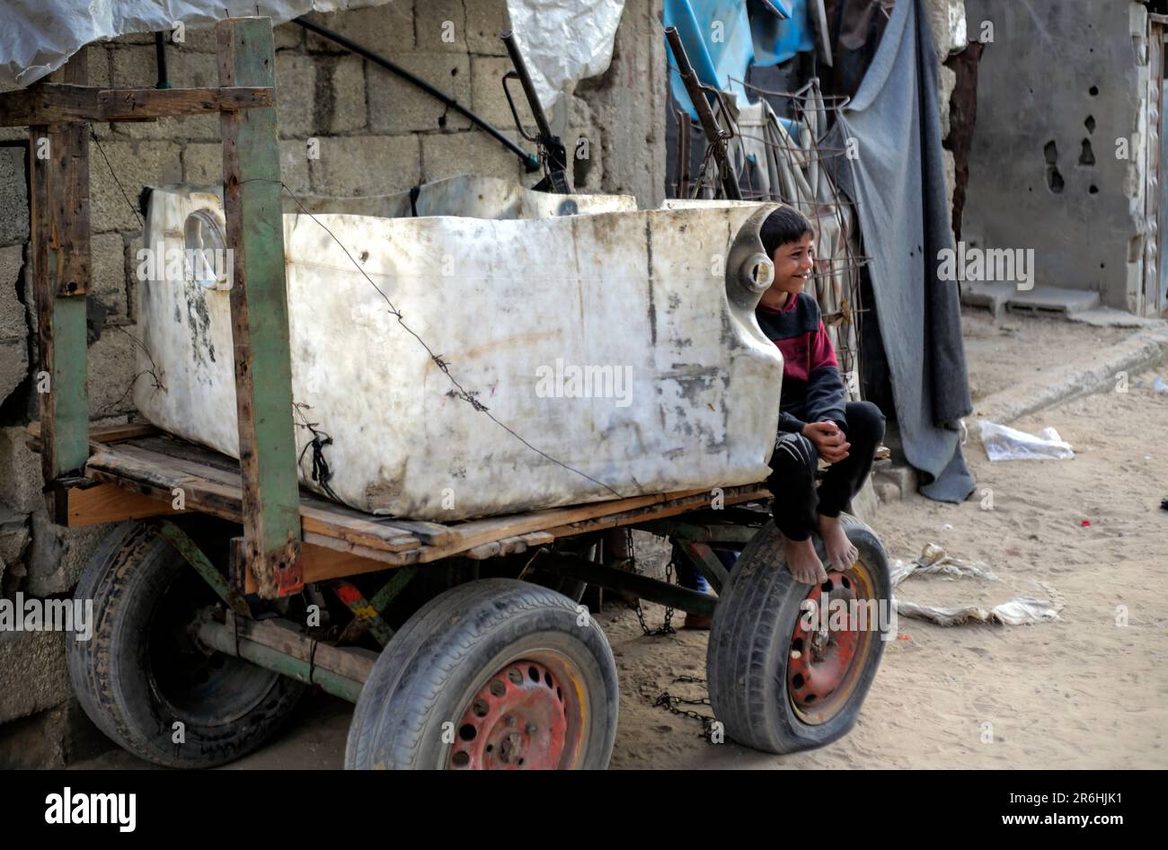 A Palestinian refugee child sits on a cart in front of his home in the ...