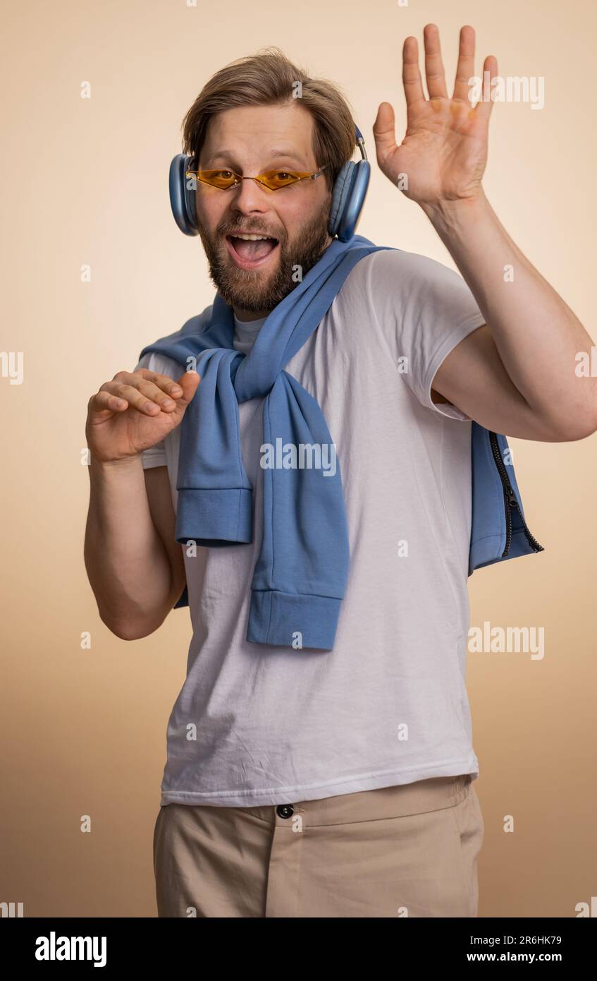 Young happy man listening music via headphones and dancing disco ...