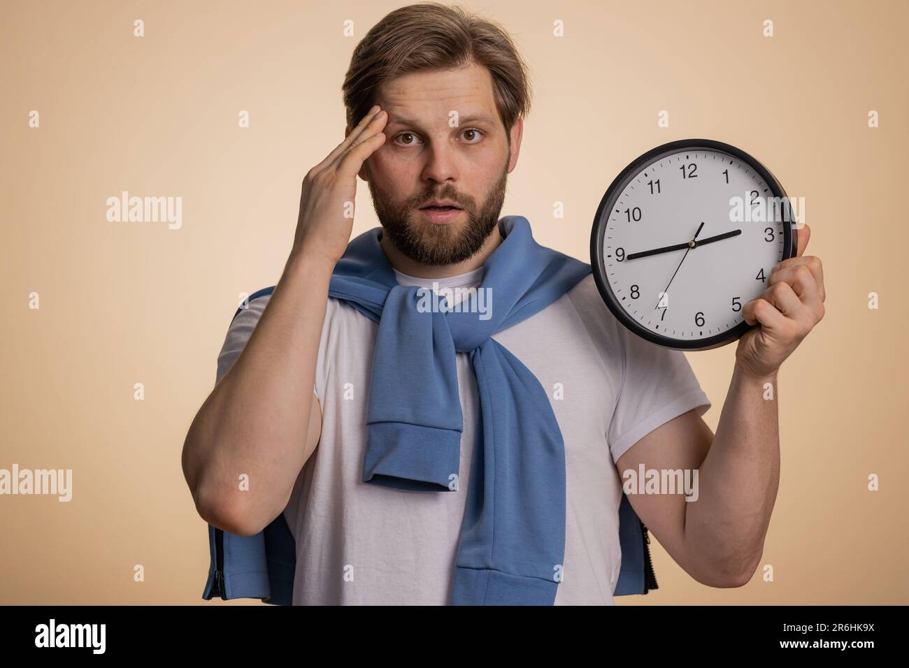 Confused man with anxiety checking time on clock, running late to work ...