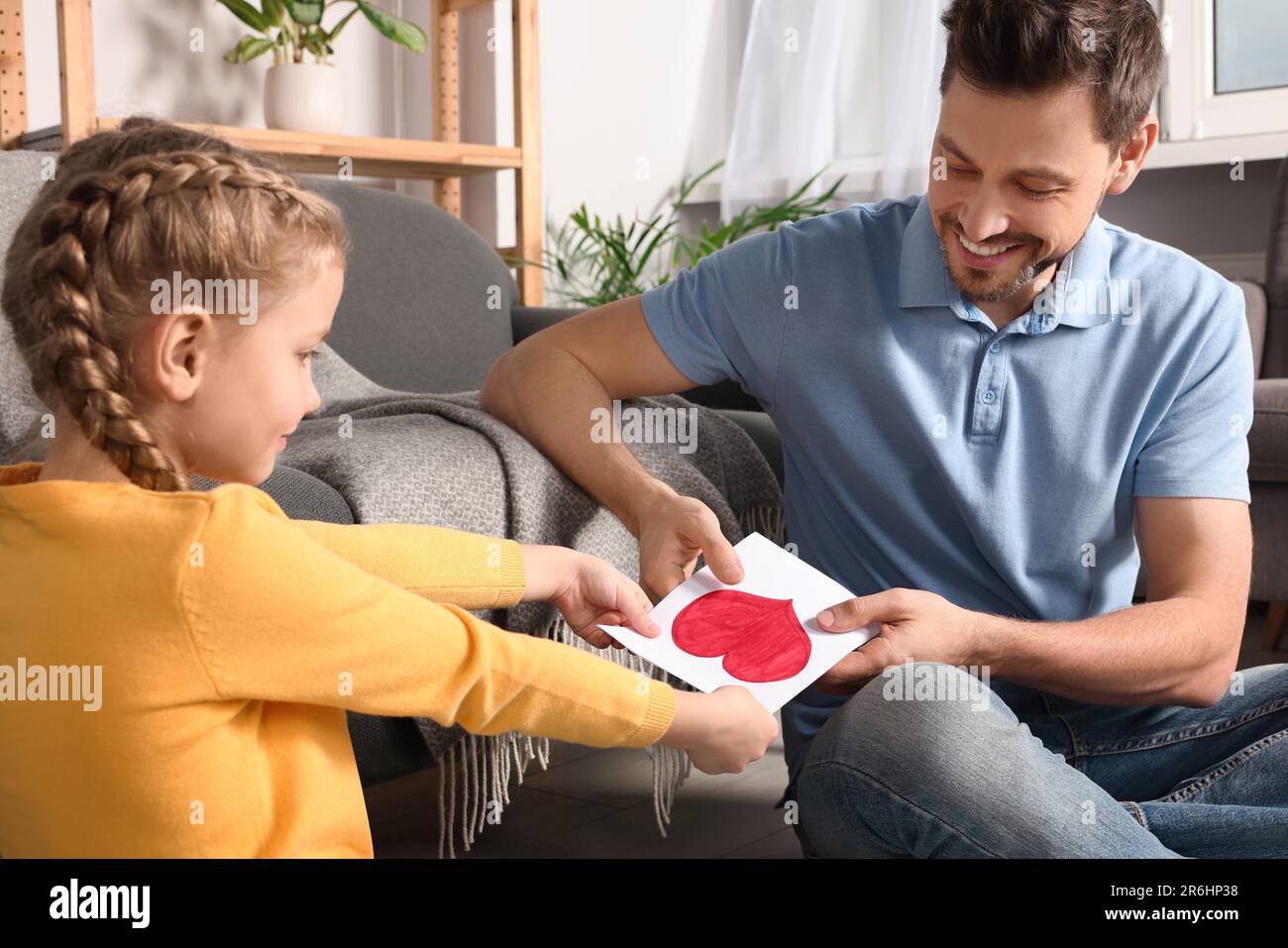 Happy man receiving greeting card from his little daughter at home ...
