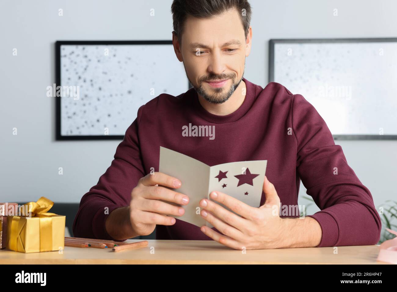 Happy man reading greeting card at wooden table in room Stock Photo - Alamy