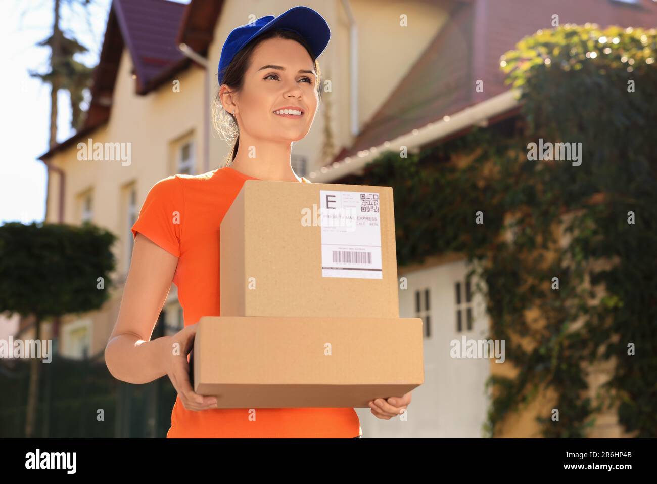 Courier carrying cardboard boxes near house on city street Stock Photo ...