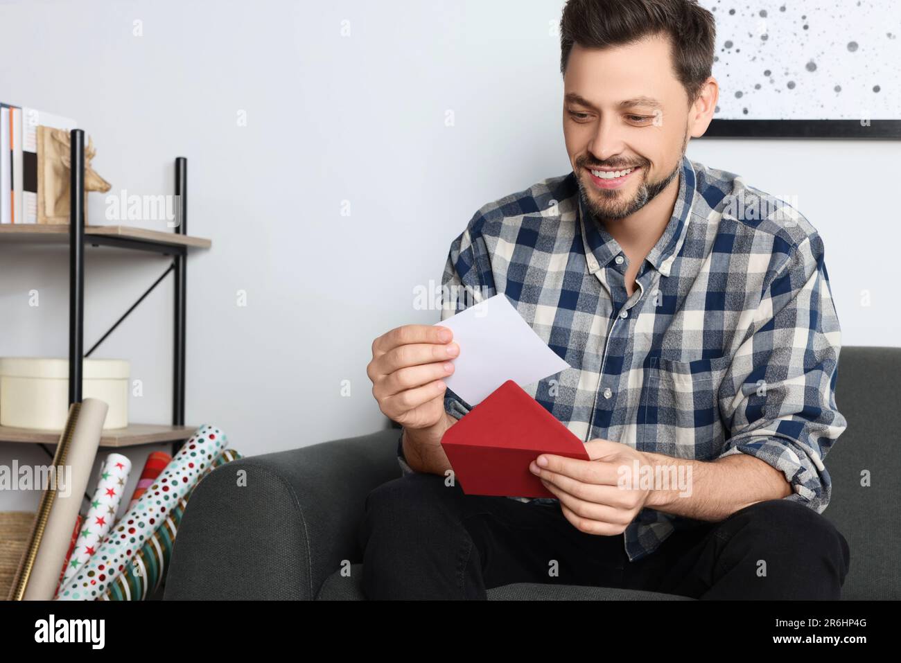 Happy man reading greeting card on sofa in living room Stock Photo - Alamy