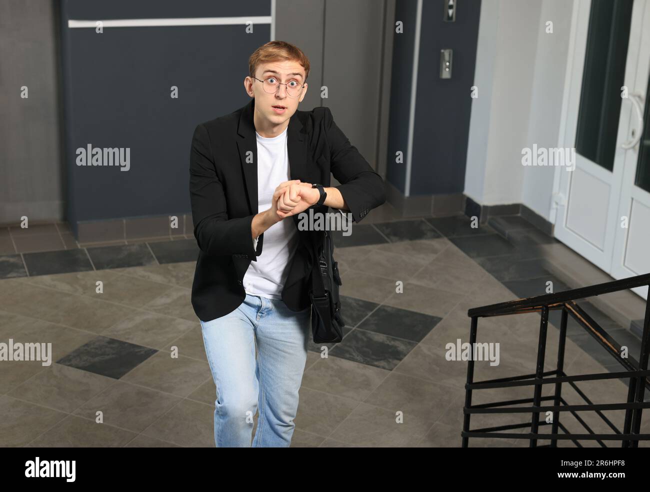 Emotional young man checking time in office. Being late Stock Photo - Alamy