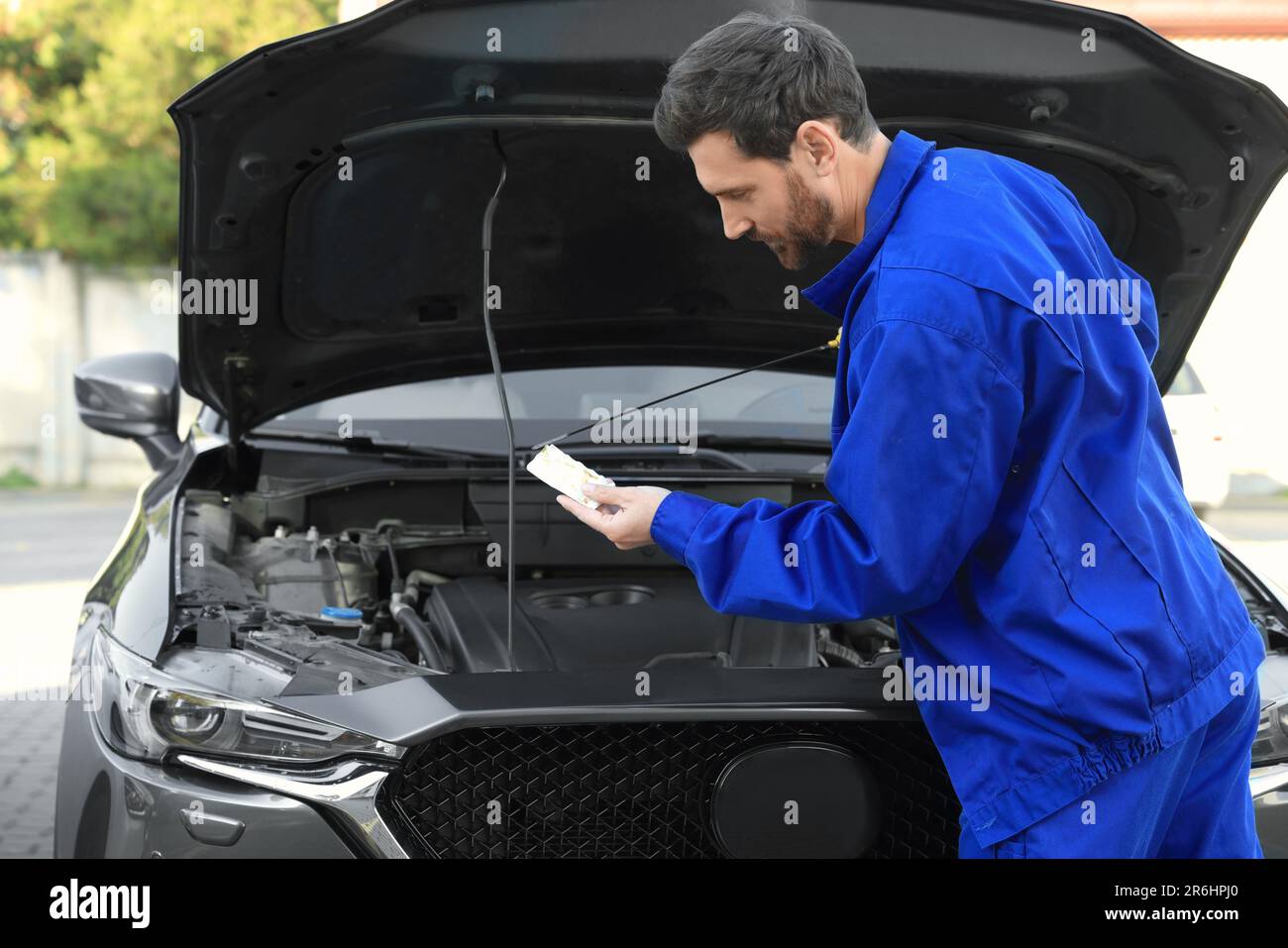 Worker checking motor oil level with dipstick outdoors Stock Photo - Alamy