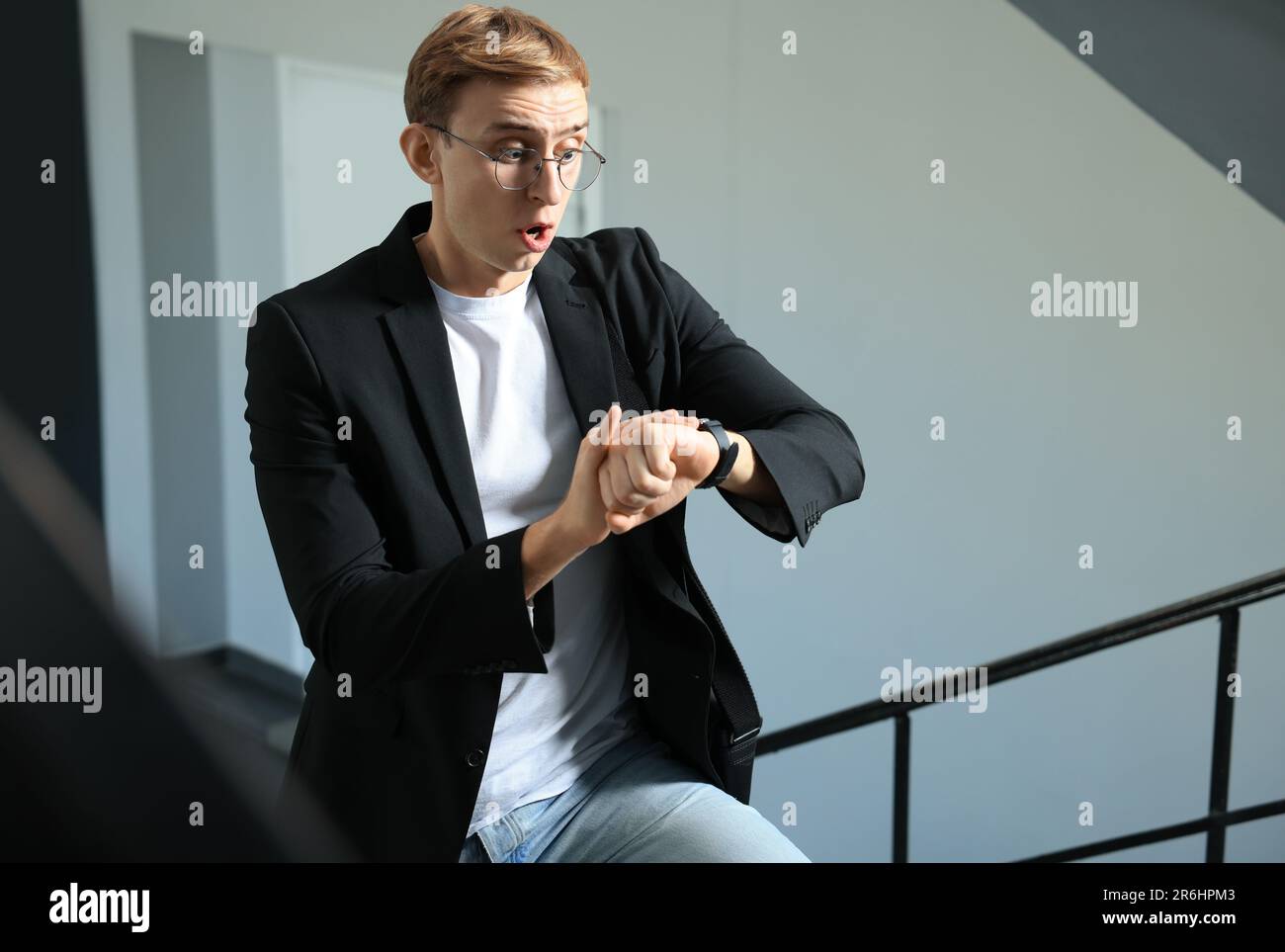 Emotional young man checking time in office. Being late Stock Photo - Alamy
