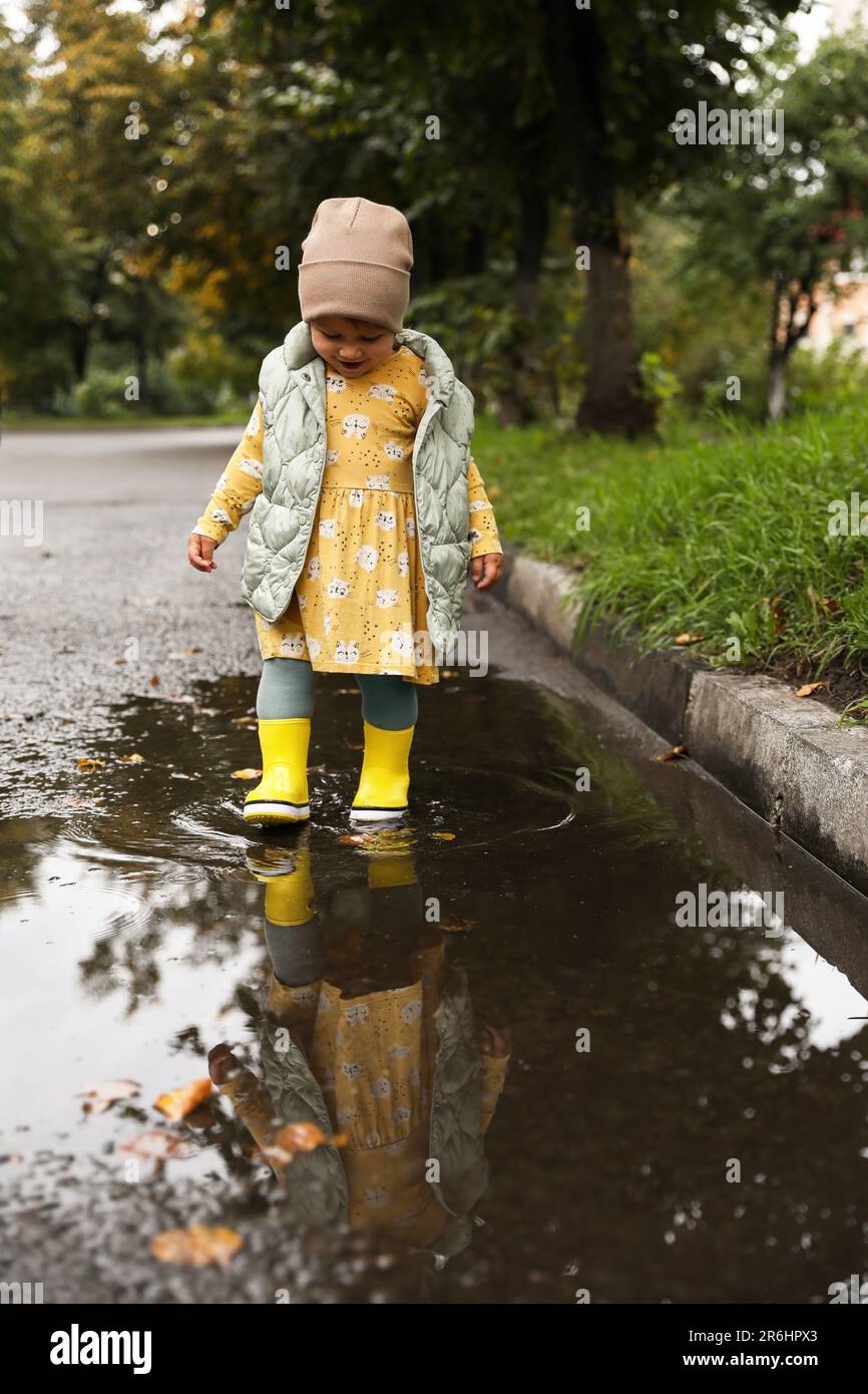 Cute little girl standing in puddle outdoors Stock Photo - Alamy