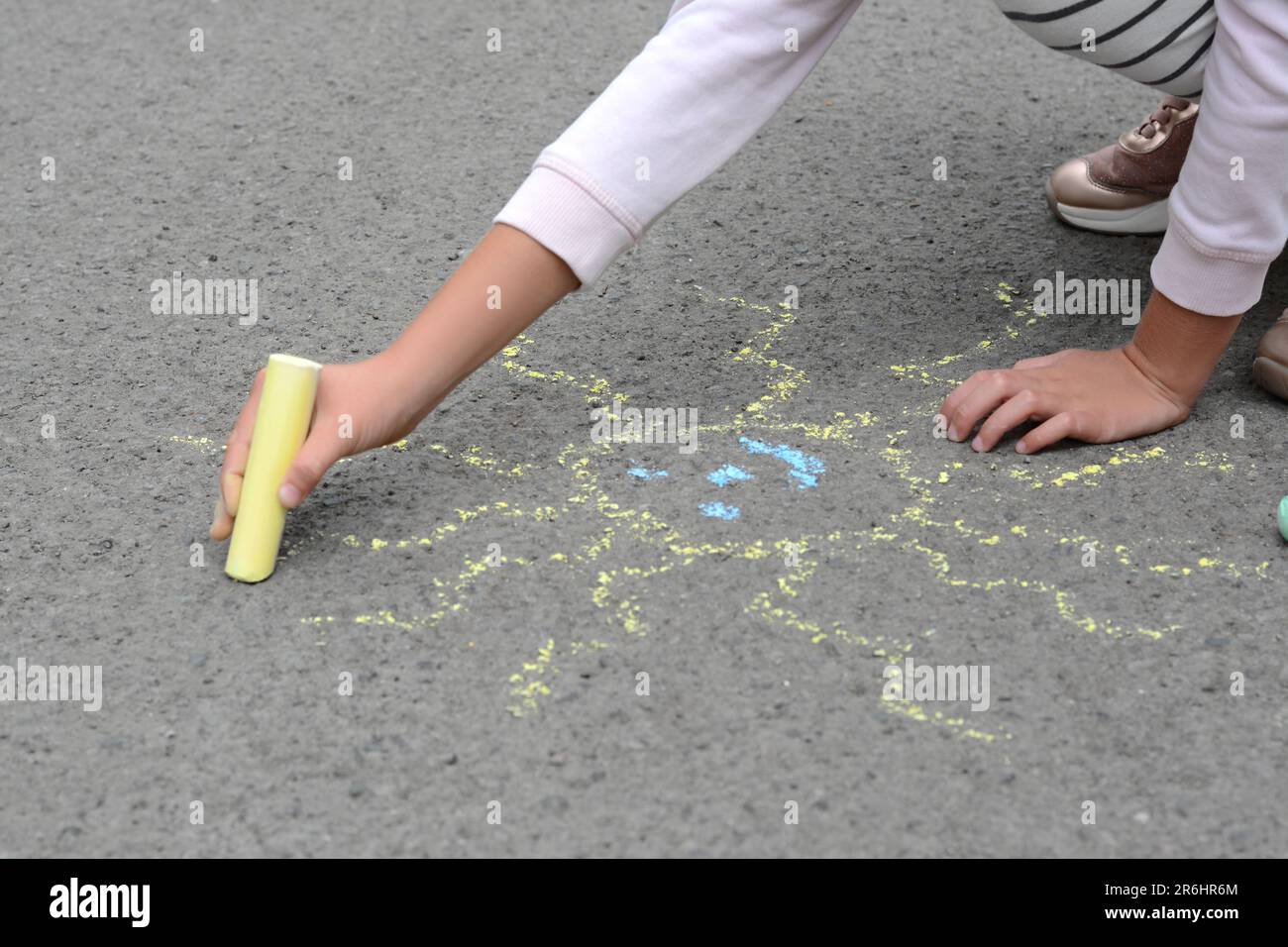Little child drawing sun with chalk on asphalt, closeup Stock Photo - Alamy