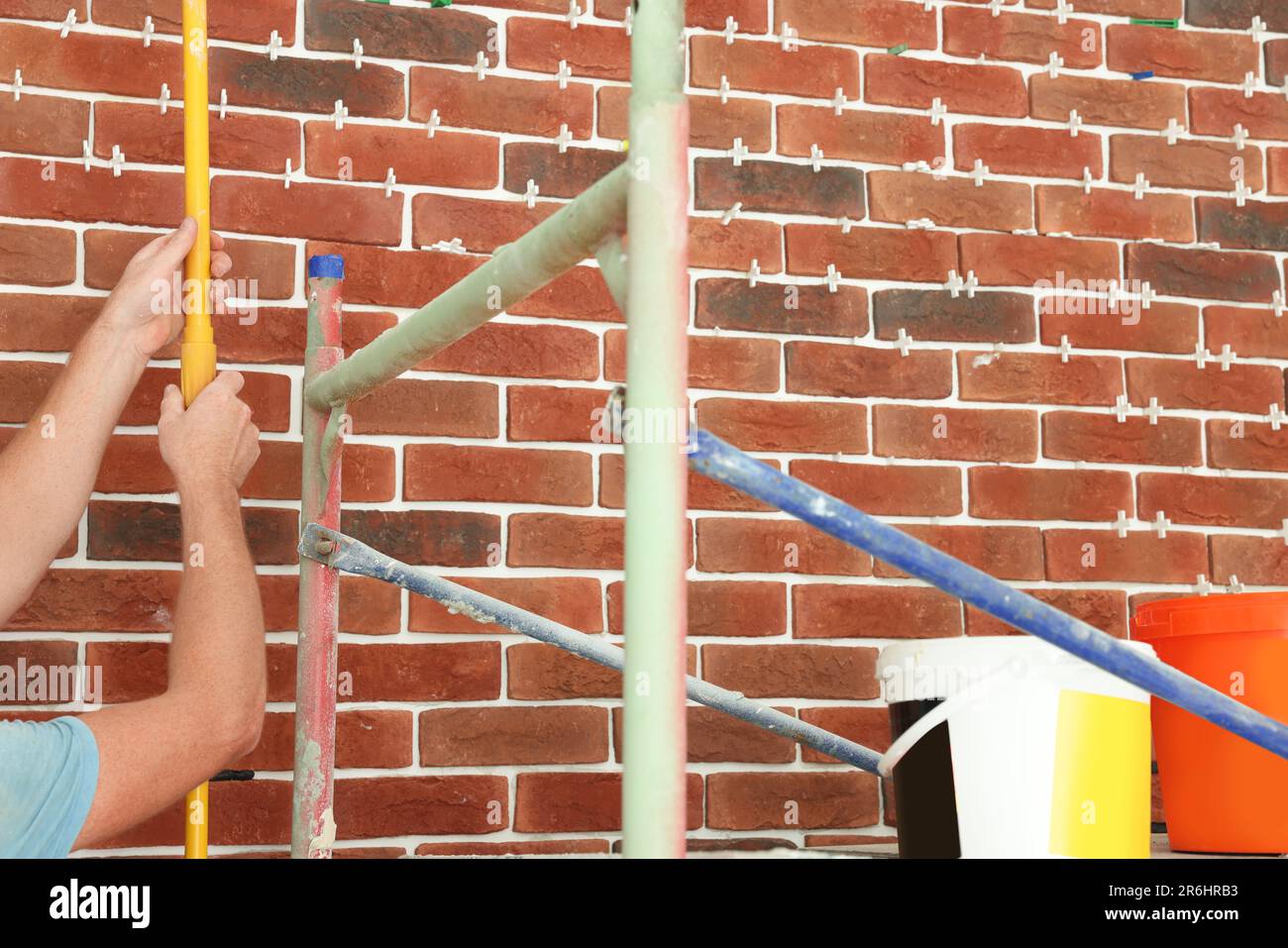 Professional builder working near brick wall, closeup. Tiles ...