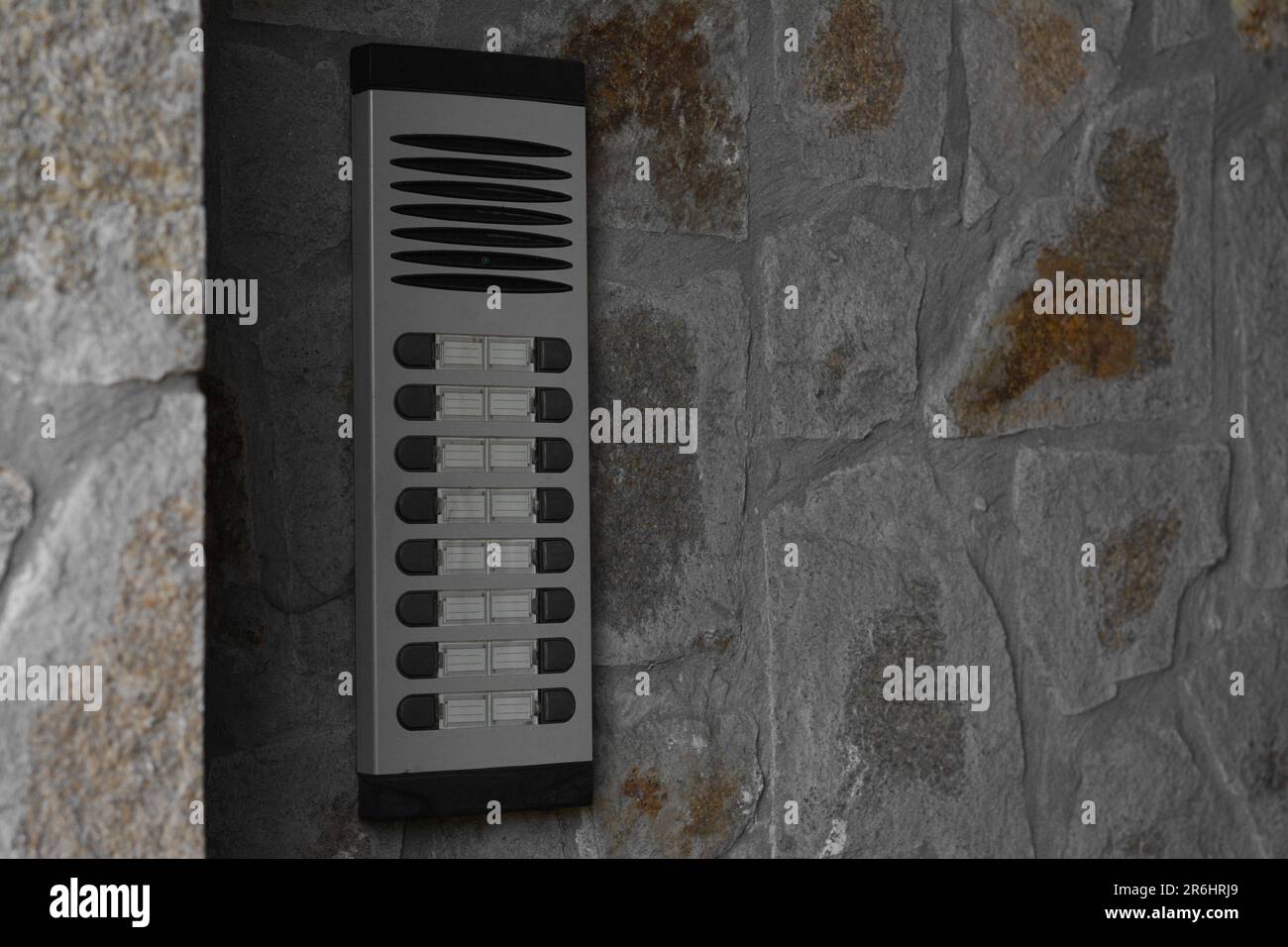 Modern intercom on concrete wall with stone fragments, space for text ...
