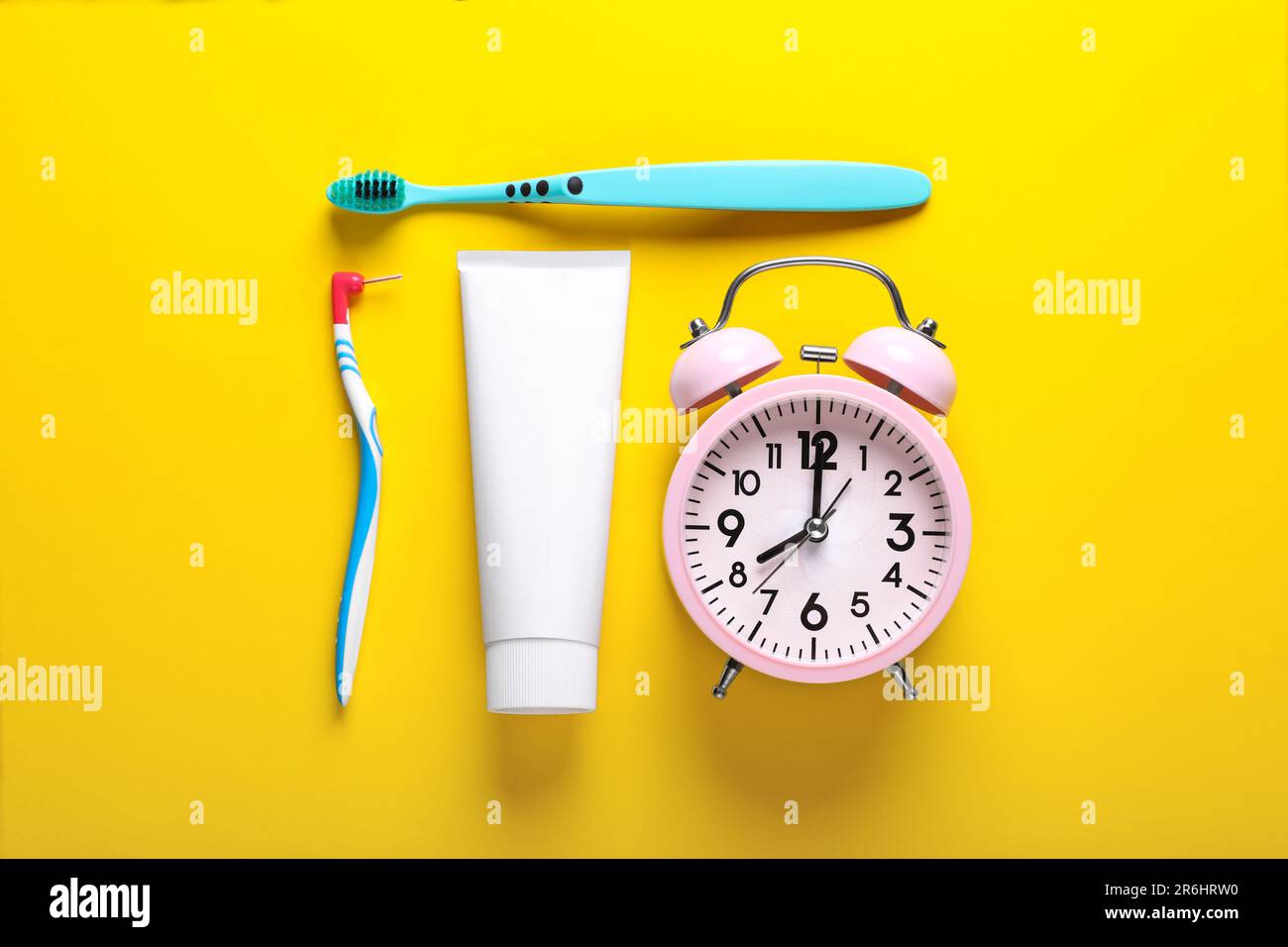 Toothpaste, toothbrushes and alarm clock on yellow background, flat lay ...