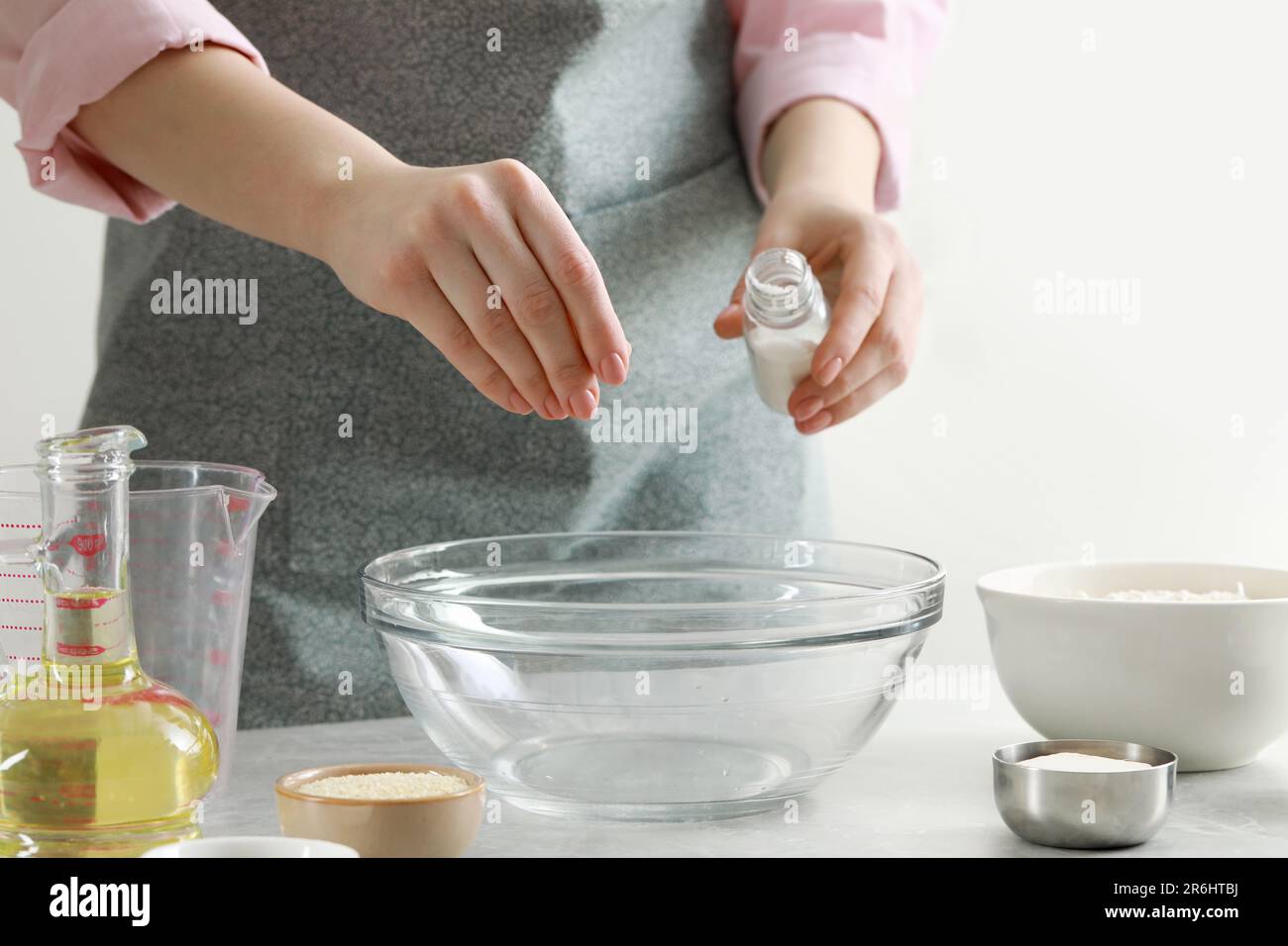 Woman adding pinch of salt into bowl at grey marble table indoors ...