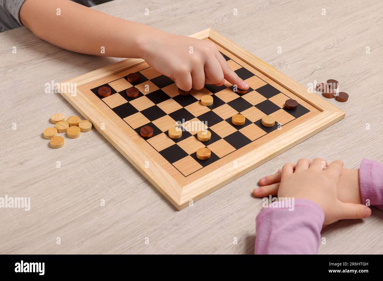 Children playing checkers at light wooden table, closeup Stock Photo ...