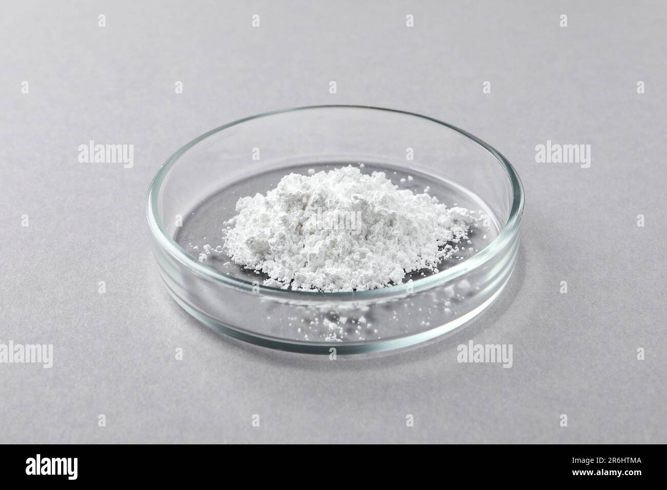 Petri dish with calcium carbonate powder on light grey table, closeup ...