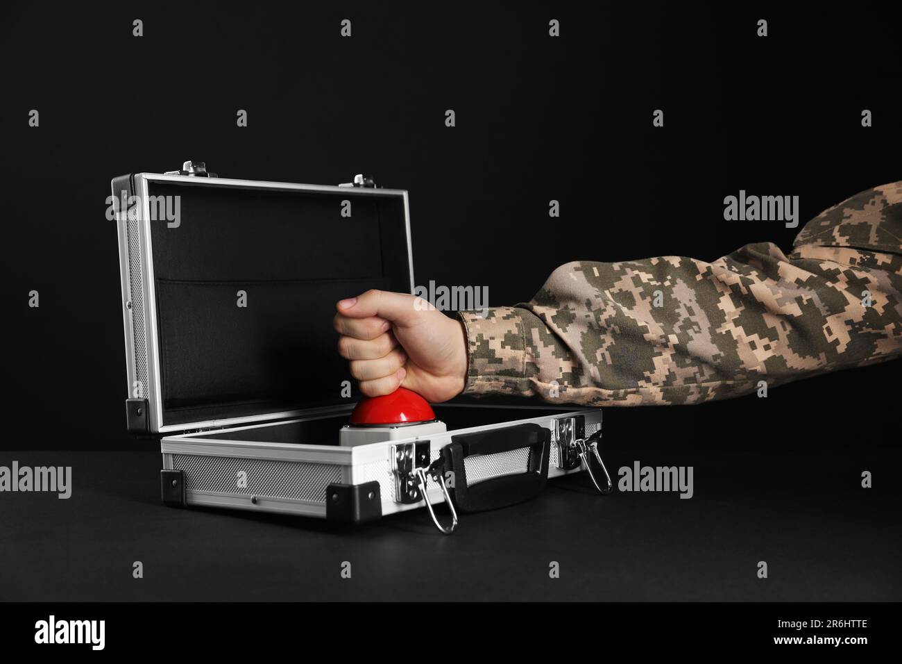 Serviceman pressing red button of nuclear weapon at black table ...