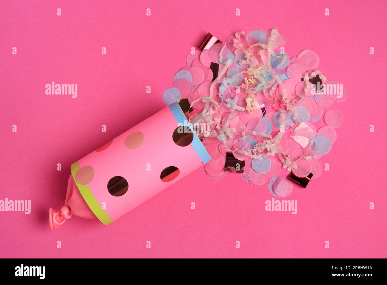 Beautiful serpentine and confetti bursting out of party popper on pink ...