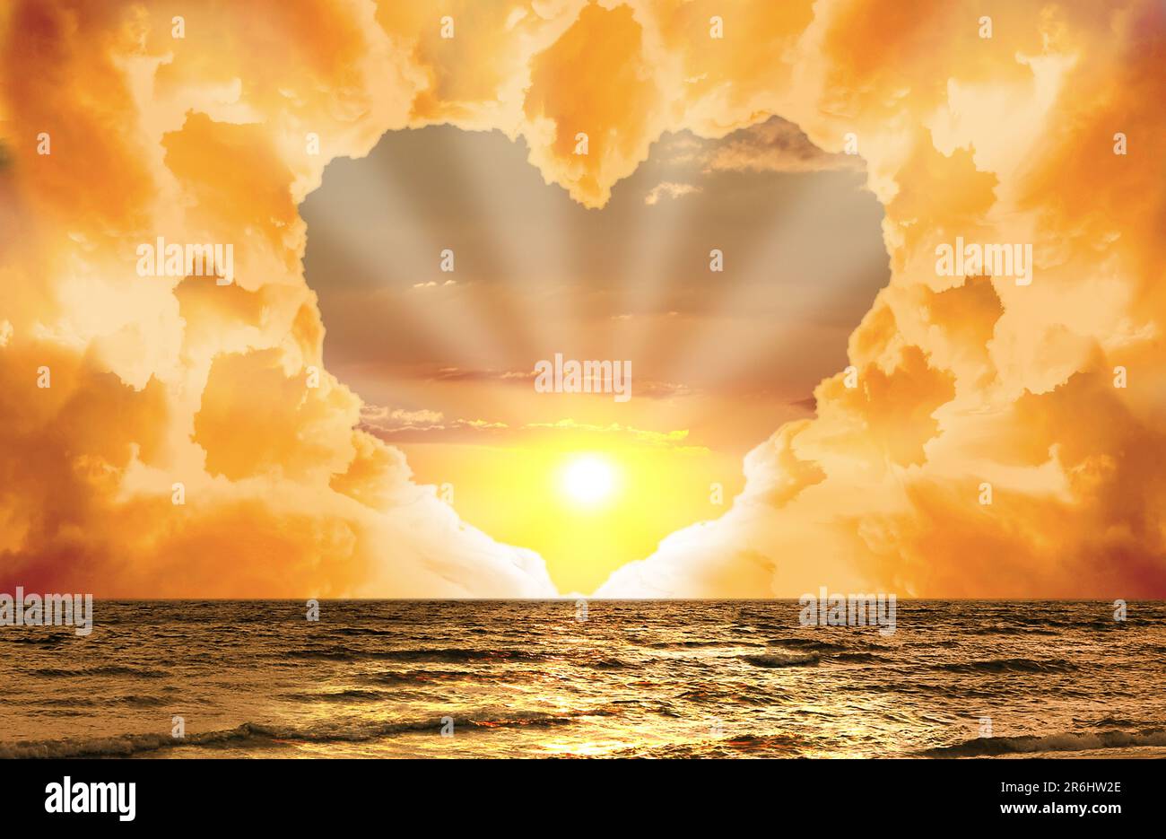 Setting sun shining through heart shaped gap formed from orange clouds ...
