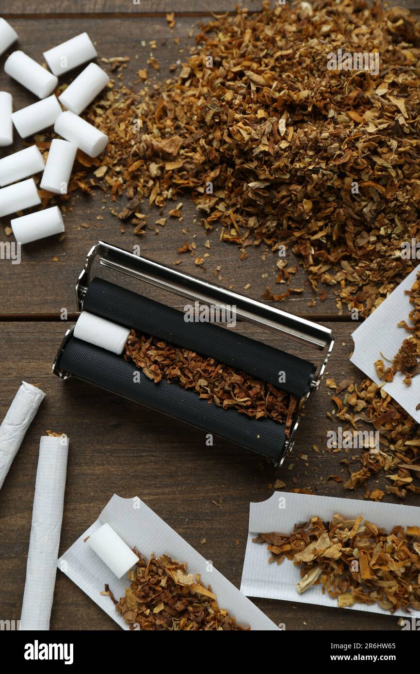Flat lay composition with roller and tobacco on wooden table. Making ...