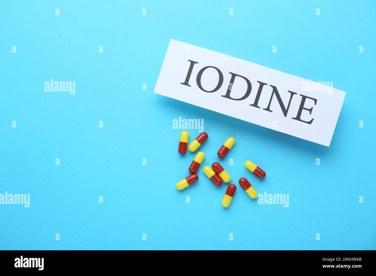 Card with word Iodine and pills on light blue background, flat lay ...